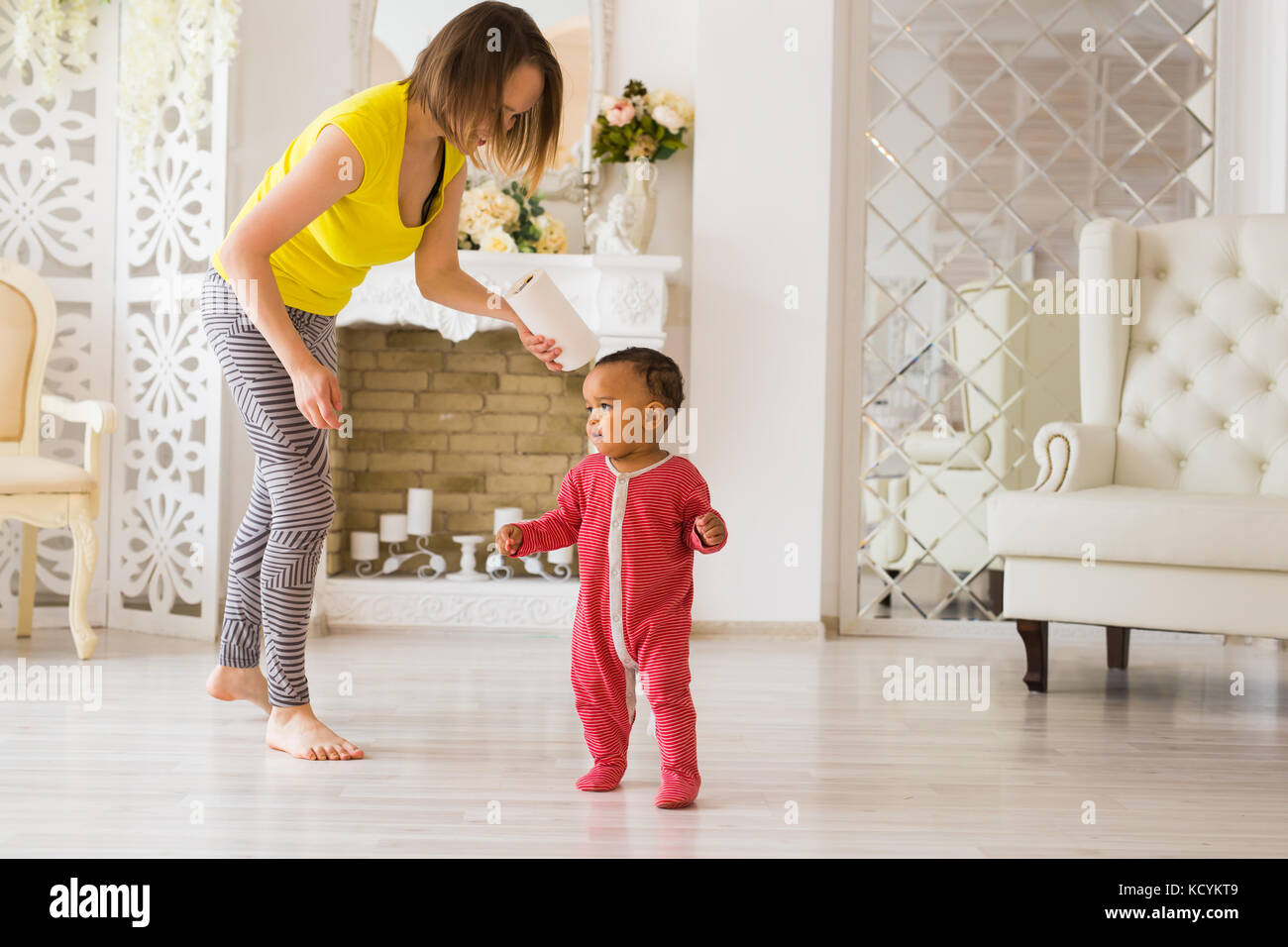 Cute little mixed race baby learning to walk, mom is holding his hands ...