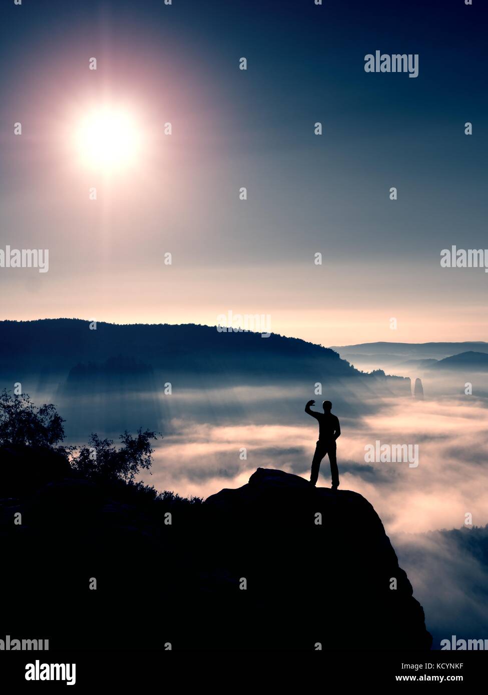 Man shadowing eyes. Alone tourist on cliff edge and watching into deep ...