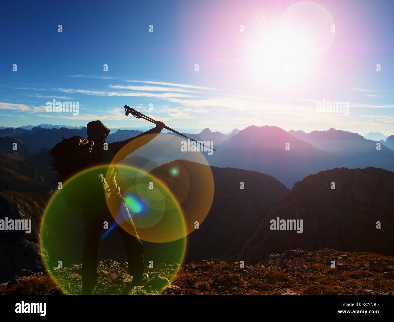 Lens flare light, strong defect. Tall backpacker with poles in hand ...