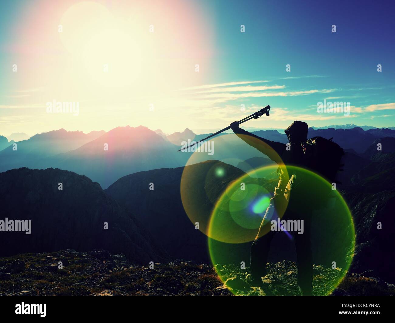 Lens flare light, strong defect. Tall backpacker with poles in hand ...