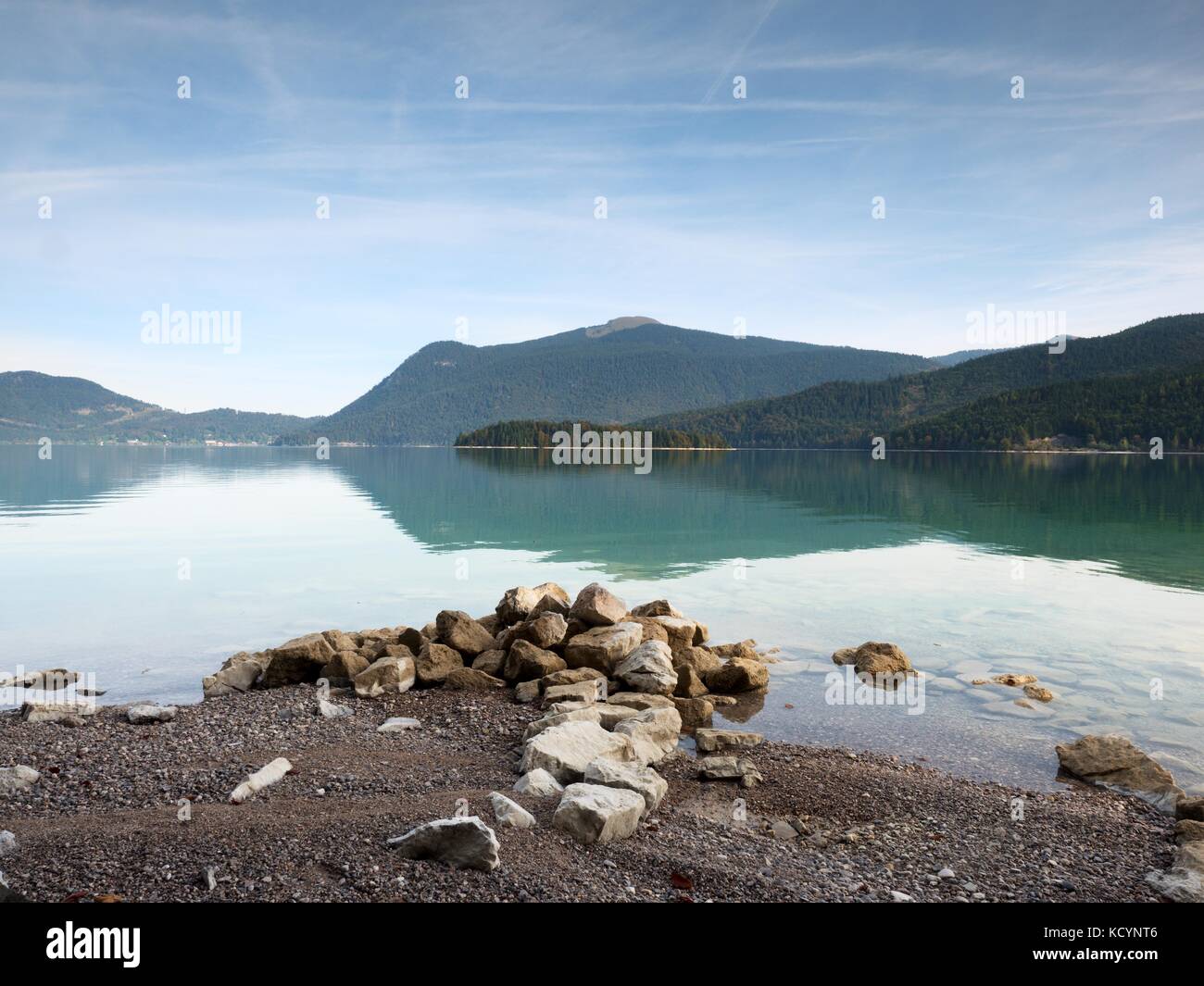 Big boulders sticking out from smooth lake water level. Green blue ...