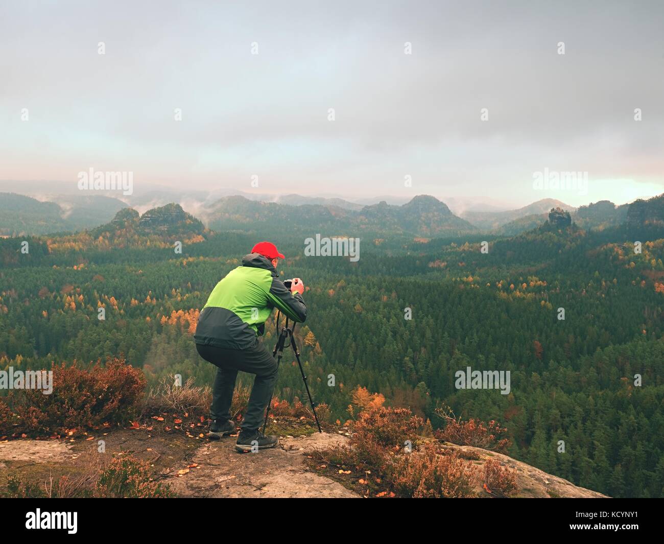 Nature photographer sit on rocky edge and takes photos with mirror ...