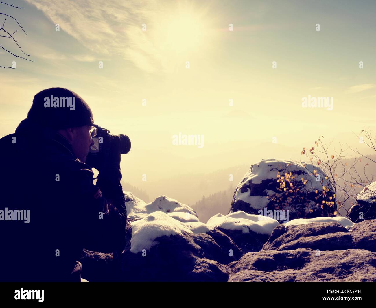 Tall man is taking photo by mirror camera on neck. Snowy rocky peak of ...