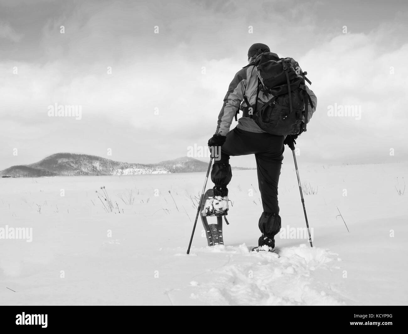 Man cleaning snowshoe. Hiker in green gray winter jacket and black ...