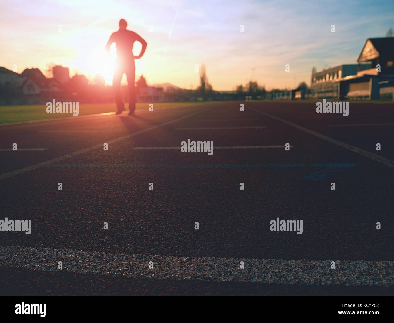 Tall man running on red running racetrack on the stadium. Sportsman in ...