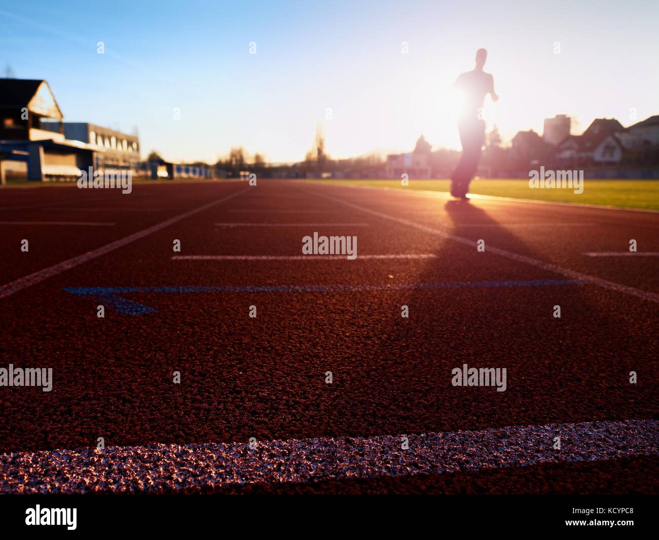 Tall man running on red running racetrack on the stadium. Sportsman in ...