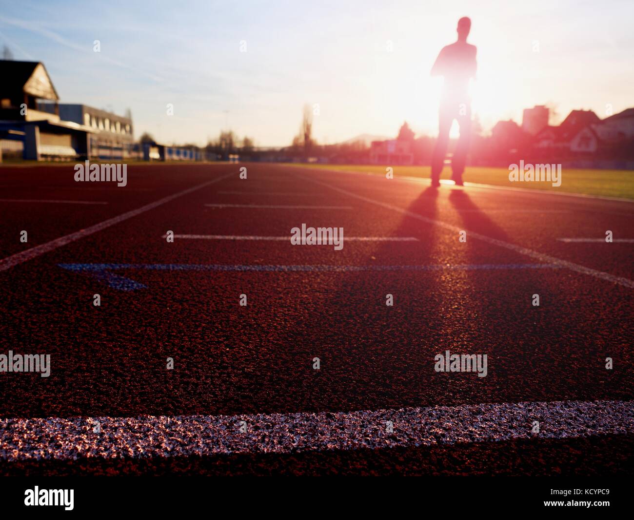Tall man running on red running racetrack on the stadium. Sportsman in ...