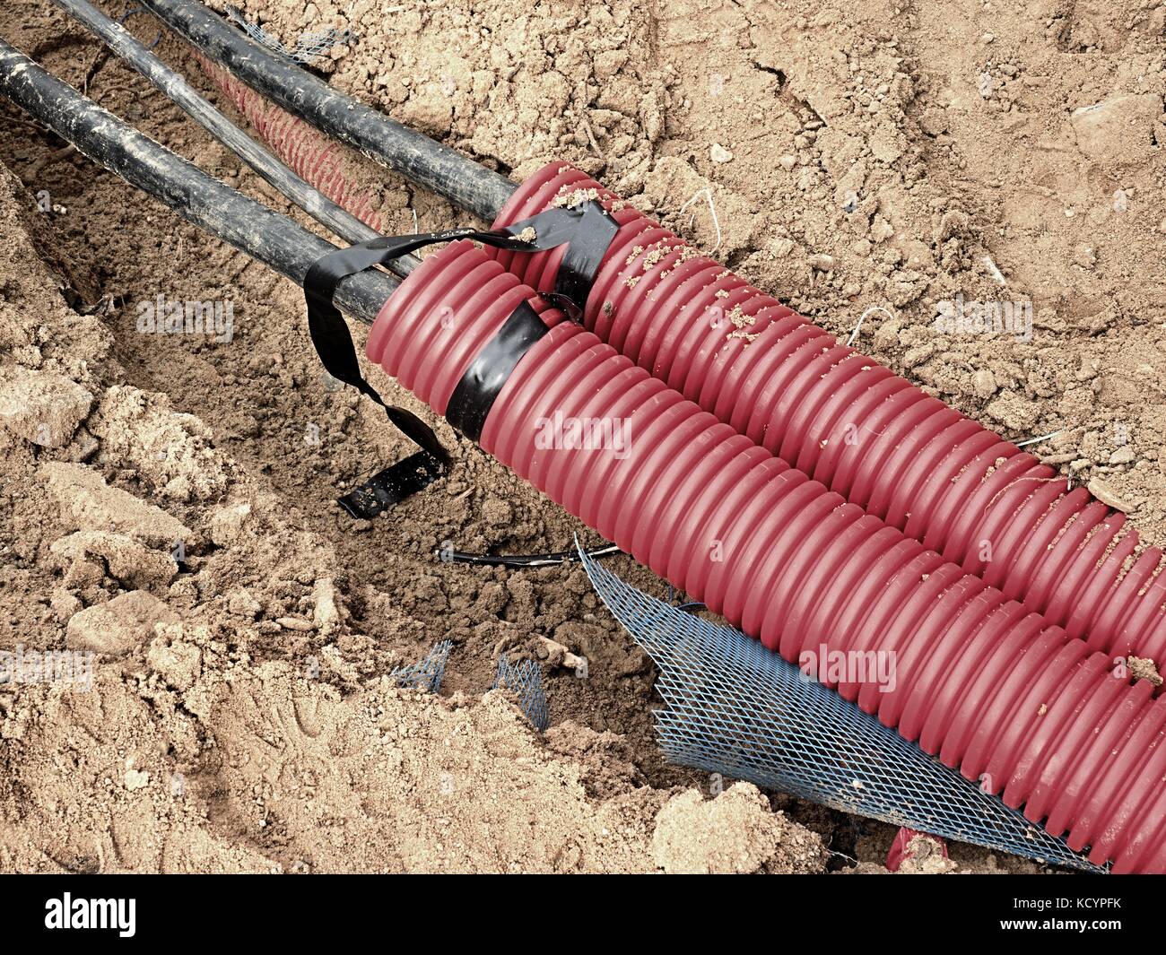Excavation of trench with black cables in protective HDPE tube. Lines ...
