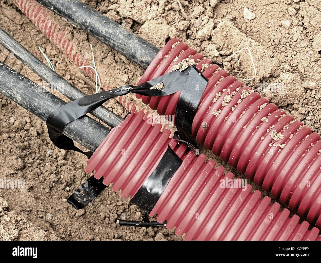Excavation of trench with black cables in protective HDPE tube. Lines ...