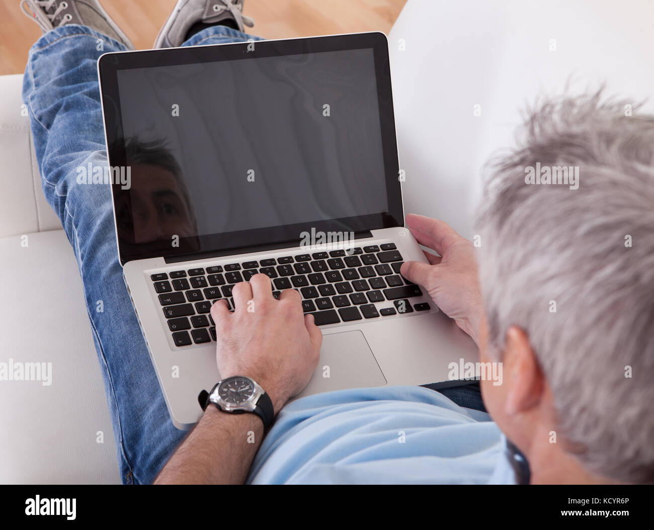 Portrait Of Happy Mature Man Using Laptop On Couch Stock Photo - Alamy