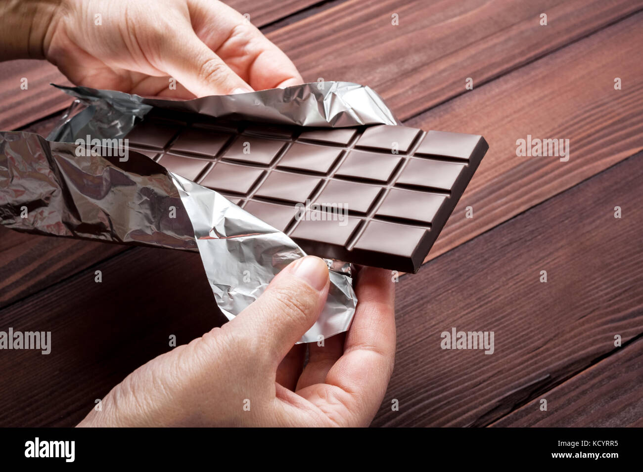 Chocolate bar in wrapper in the hands. Top view Stock Photo - Alamy