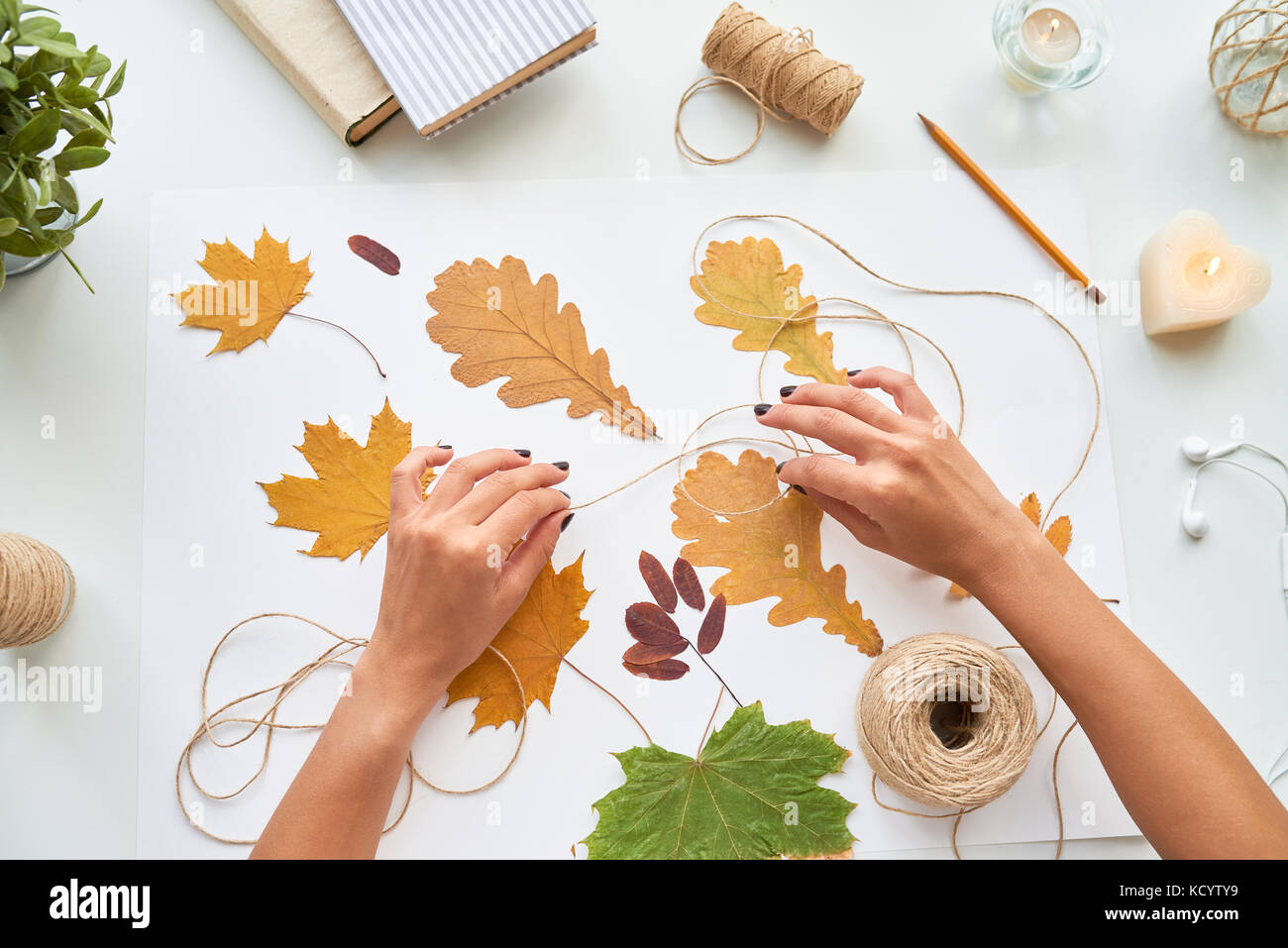 Top view of female hands making handmade autumn leaves decoration for ...