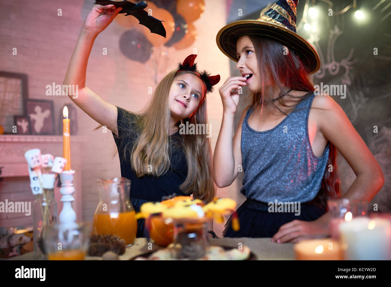 Portrait of two teenage girls wearing Halloween costumes playing with ...