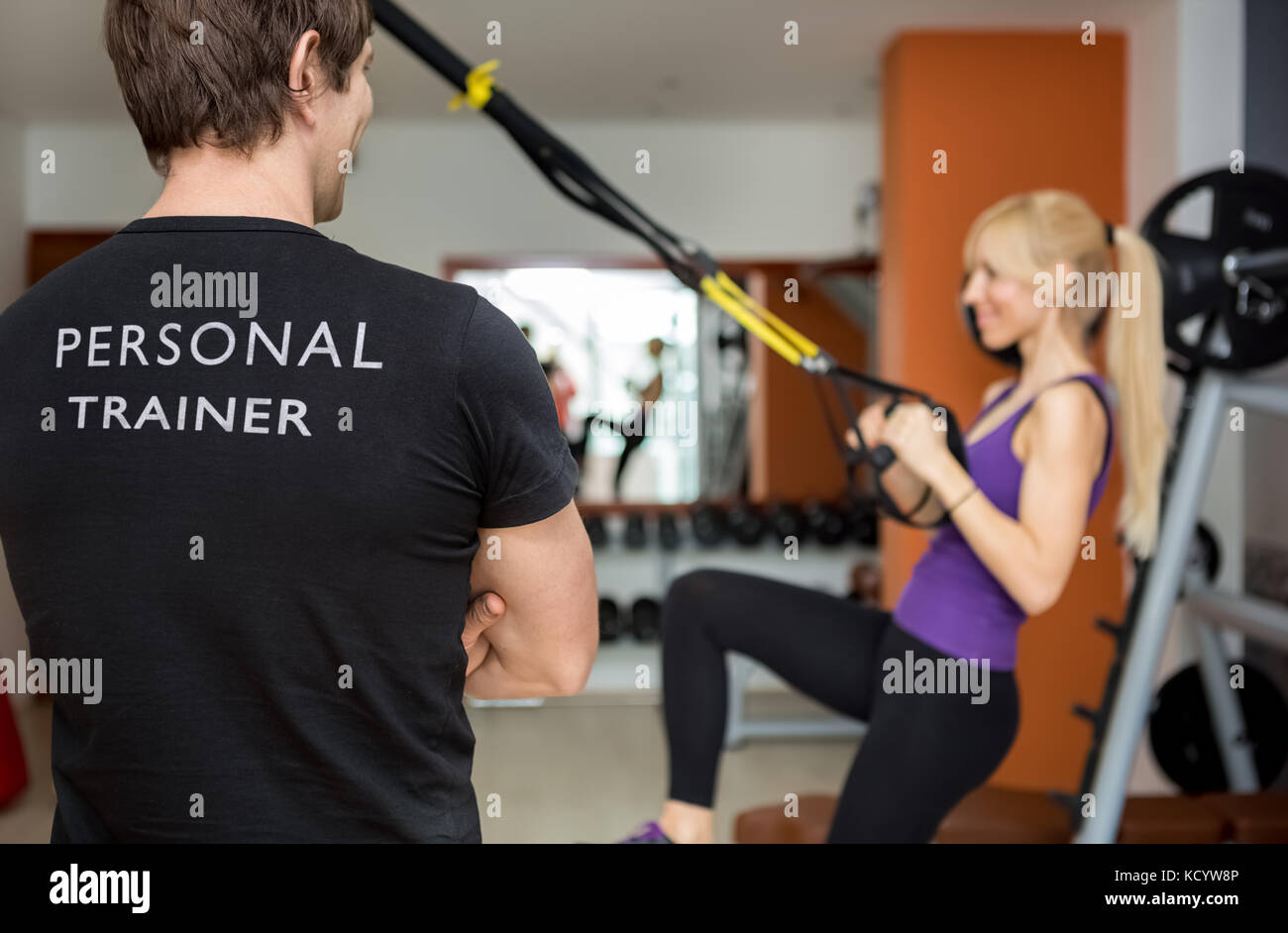 Personal trainer, with his back facing the camera, looking at his ...