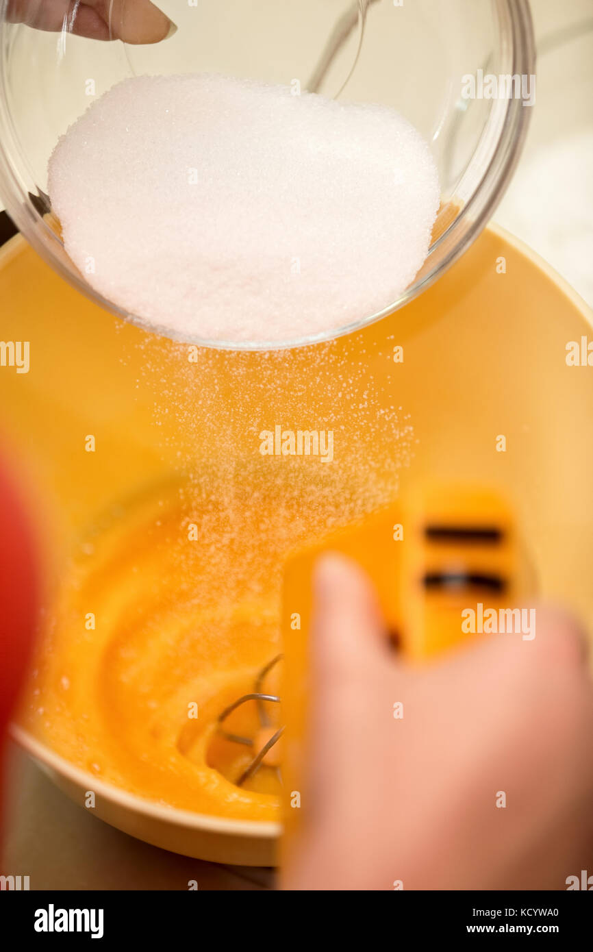 Pouring sugar into bowl with cake mixture Stock Photo - Alamy