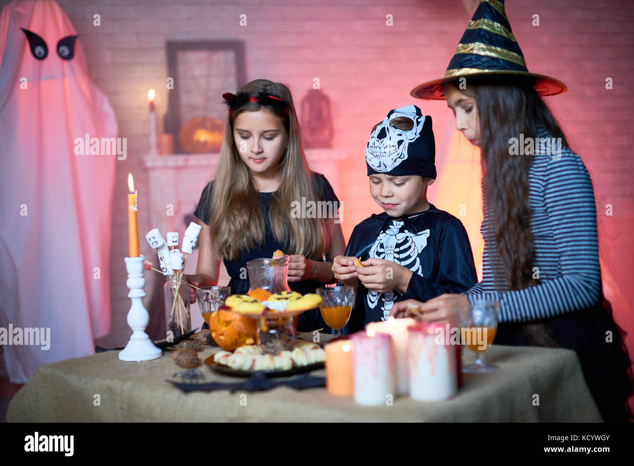 Cute little friends in fancy costumes gathered together at Halloween ...