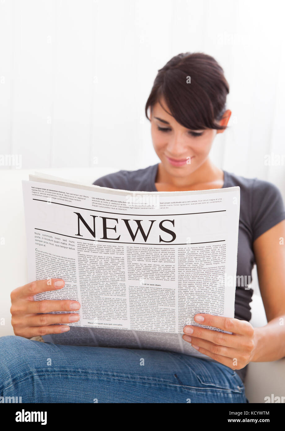 Young Happy Woman Reading Newspaper On Couch Stock Photo - Alamy
