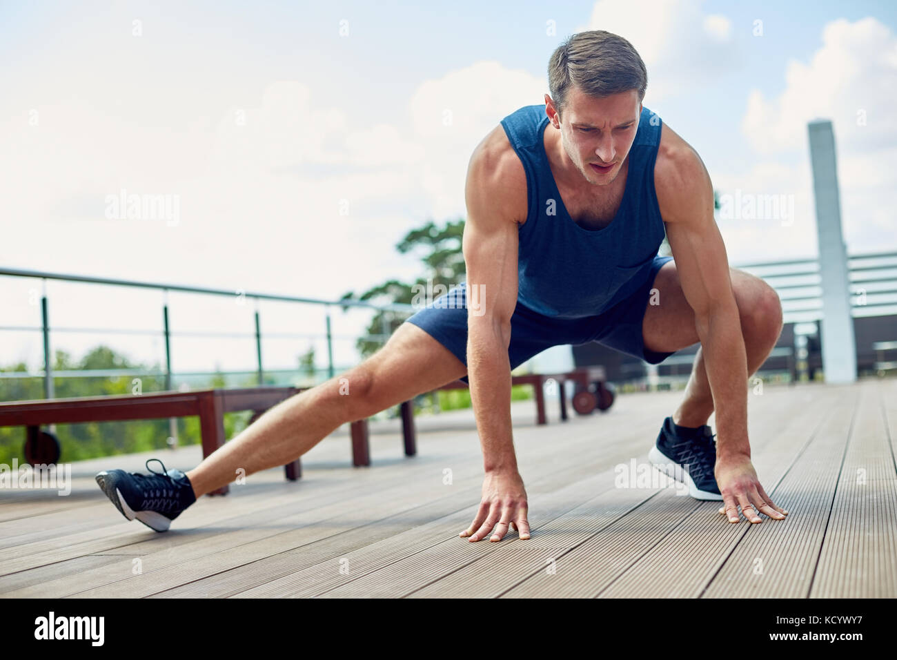 Full length portrait of concentrated young runner stretching legs ...