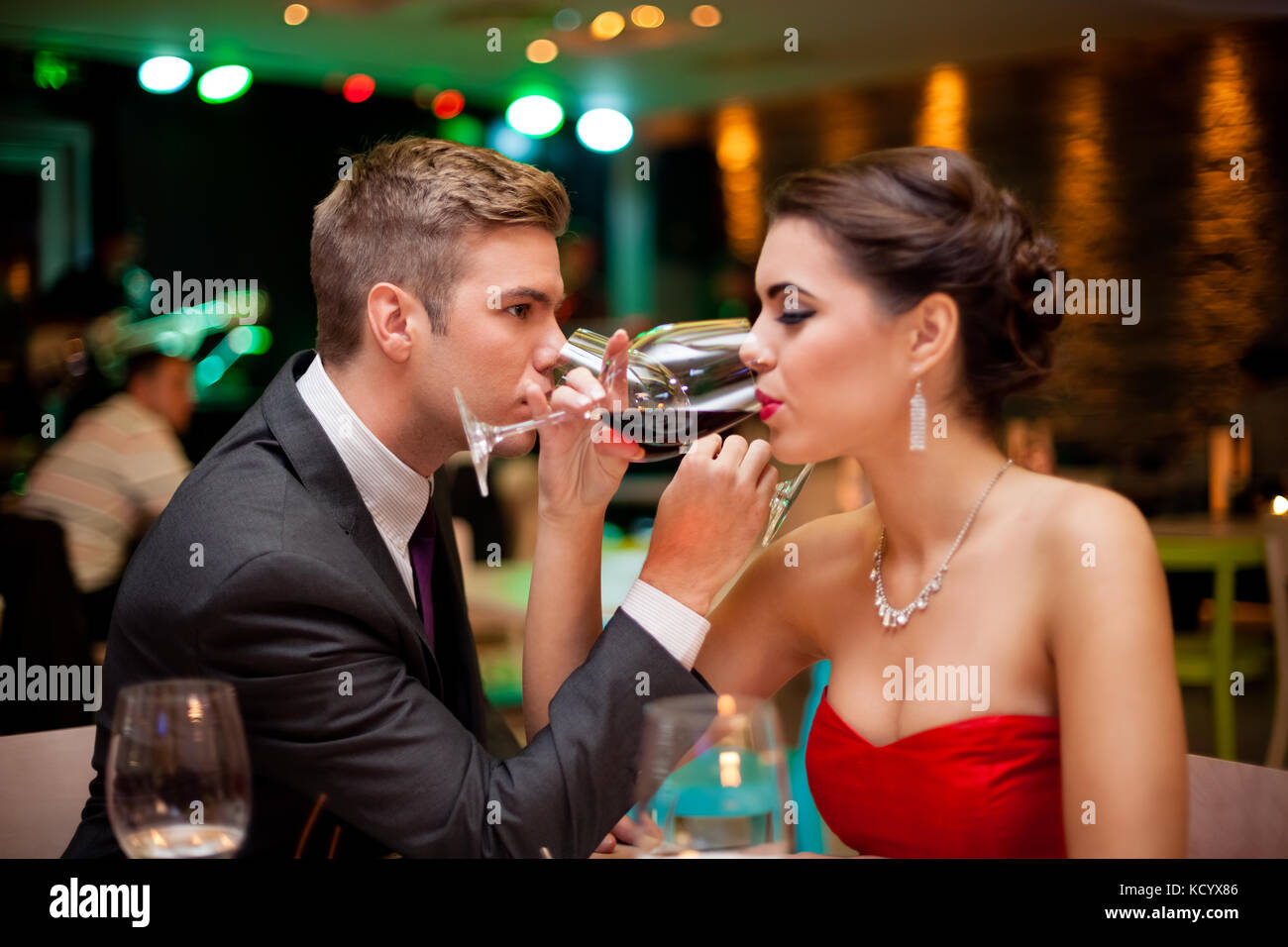 Romantic couple drinking wine with crossed arms Stock Photo - Alamy