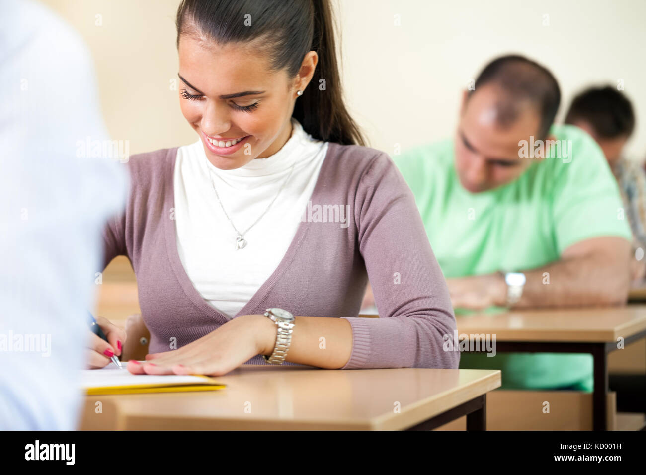 Cheerful young student doing test in classroom Stock Photo - Alamy