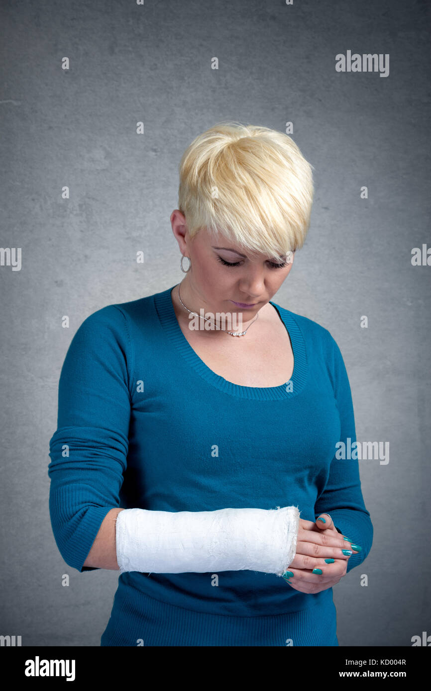 Sad woman looking at broken arm on her arm Stock Photo - Alamy