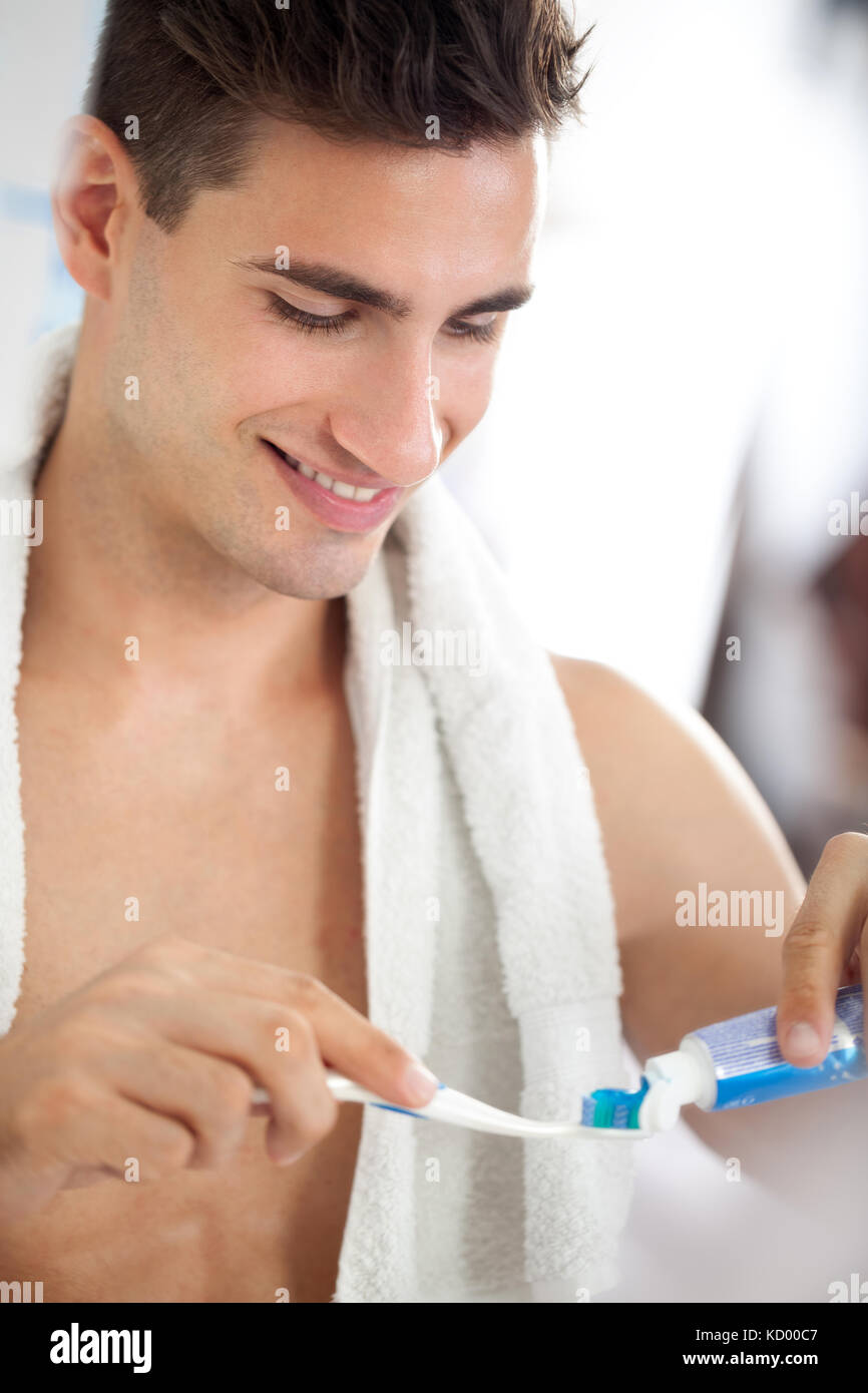 Handsome young man squeezes toothpaste on the brush in bathroom Stock ...