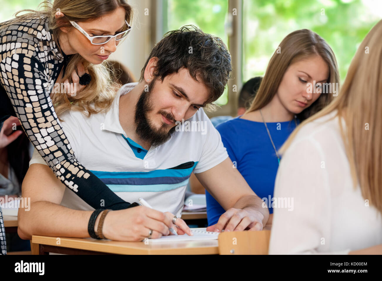Female teacher helping student in class Stock Photo - Alamy
