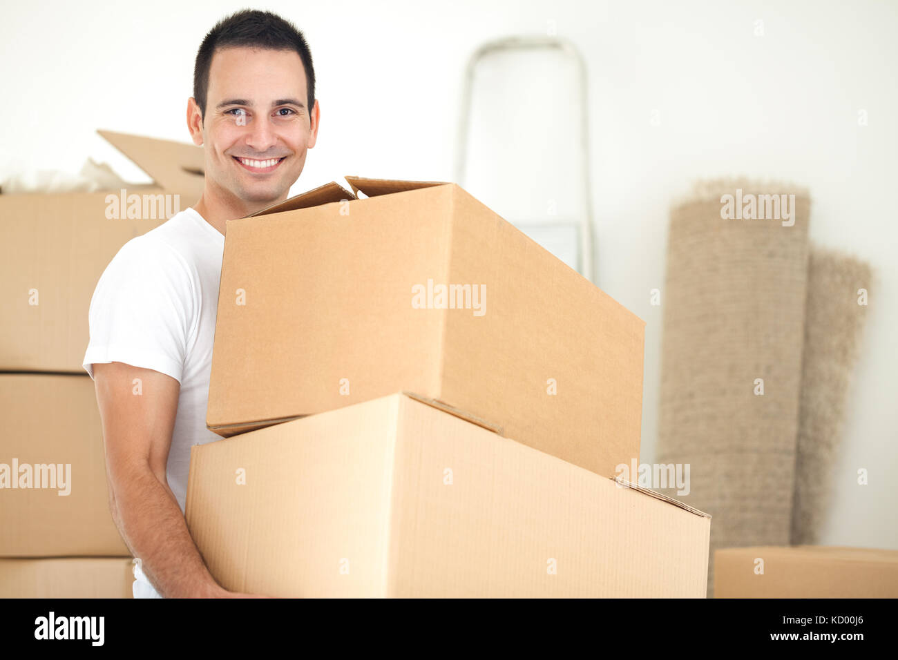 Smiling handsome man carrying packages during moving house Stock Photo ...