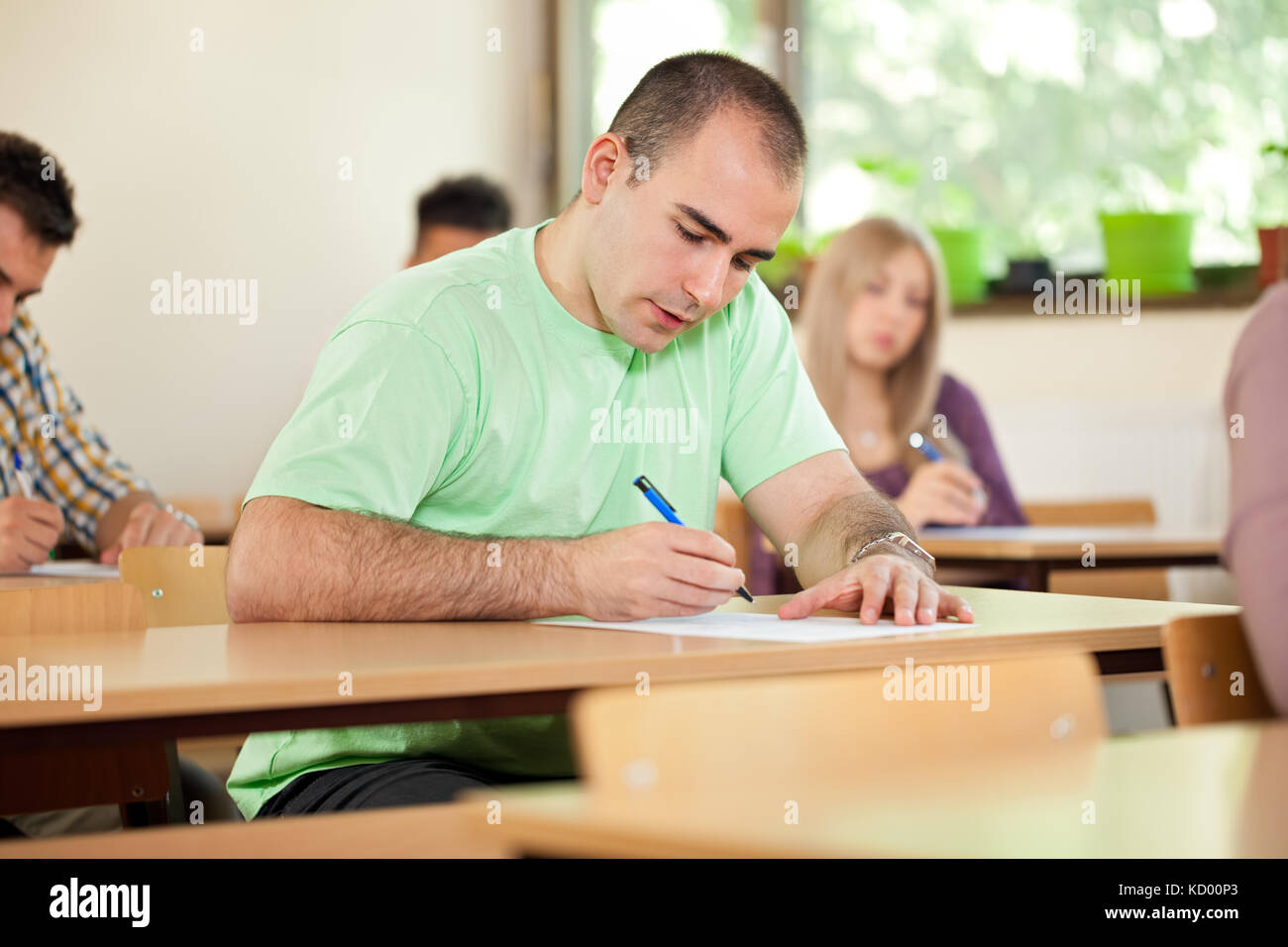Handsome student doing test in a classroom Stock Photo - Alamy