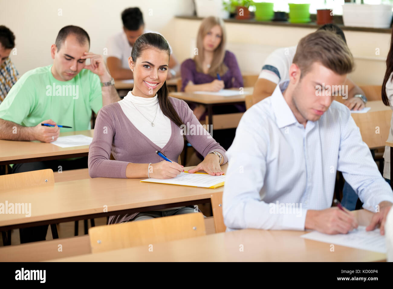 Beautiful student girl in classroom full of students Stock Photo - Alamy