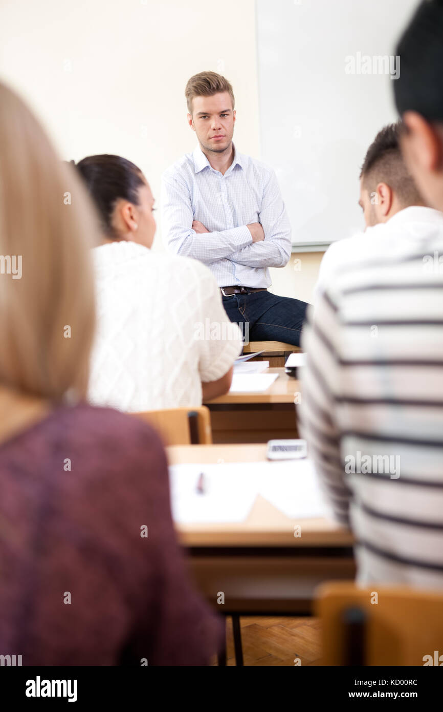 Young tutor teaching class of students in classroom Stock Photo - Alamy