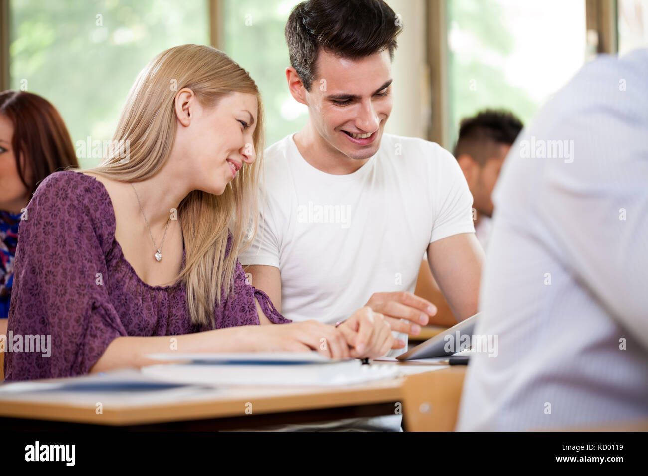 Couple of students talking in class and smiling Stock Photo - Alamy
