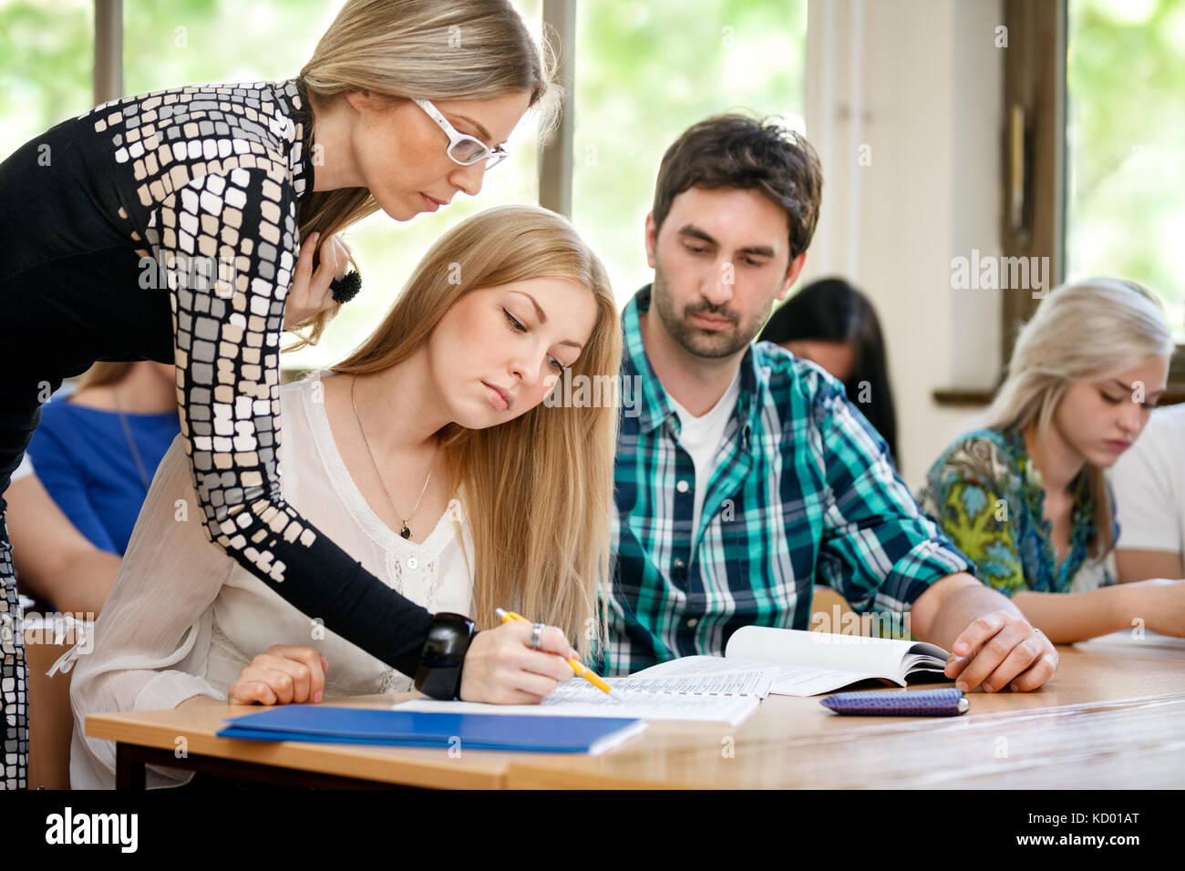 Teacher helping student girl in class Stock Photo - Alamy