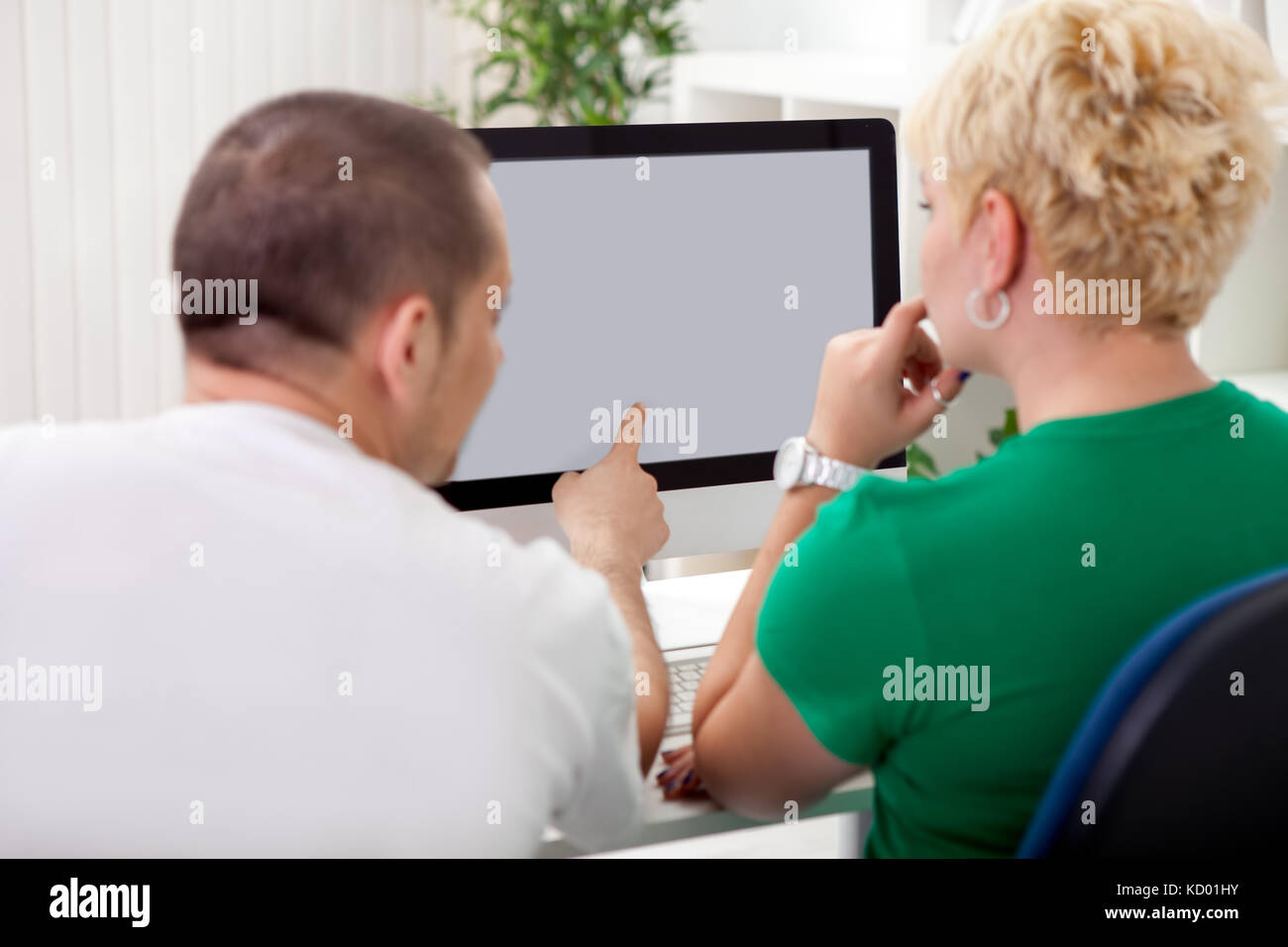 business colleagues working on computer together in office, back view ...