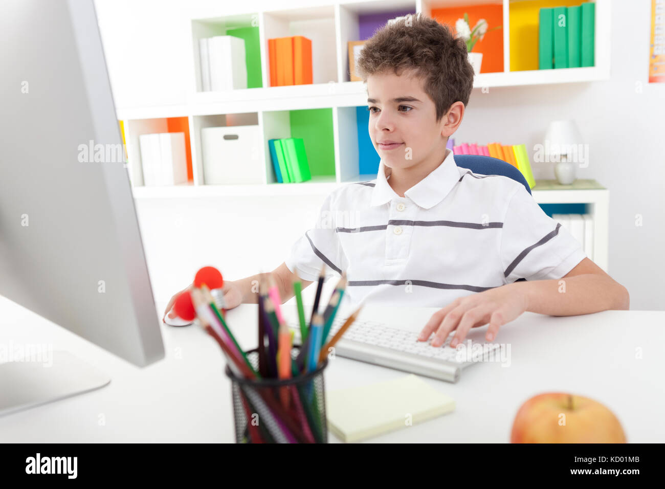 Smiling little boy sitting at desk and using computer Stock Photo - Alamy