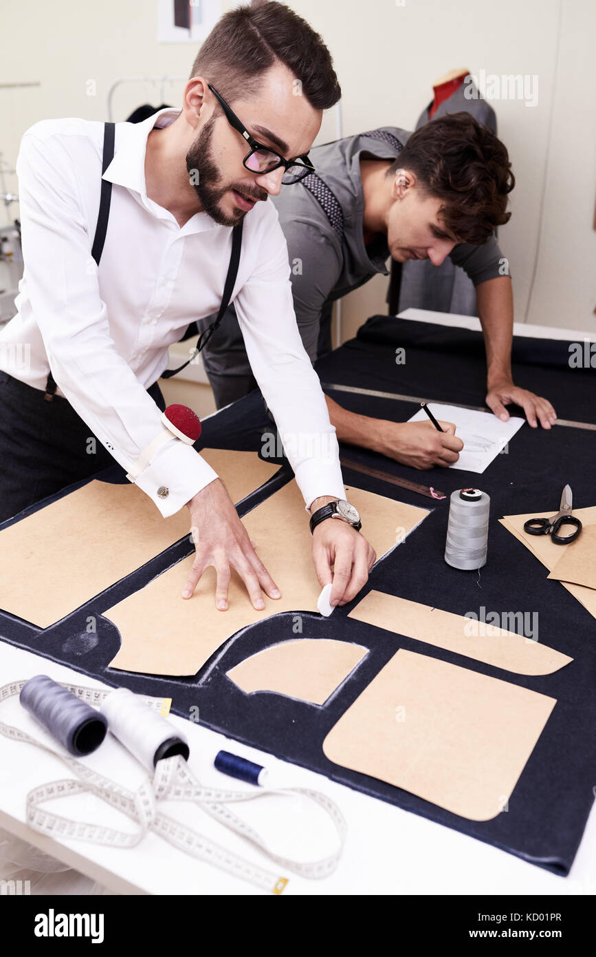 Portrait of two young tailors working in atelier studio, making ...