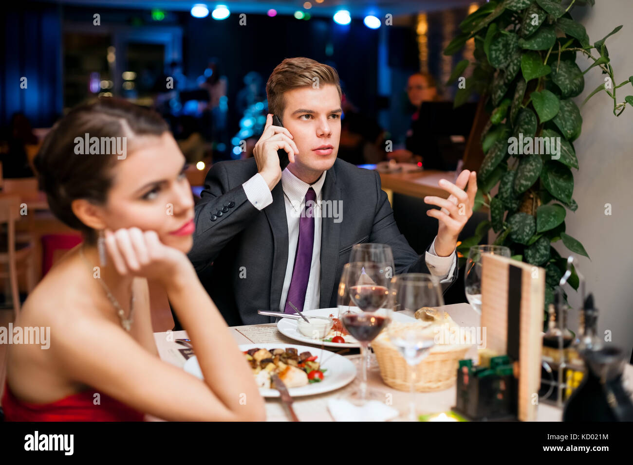 Man talking on a cell phone while on a date with his girlfriend or wife ...
