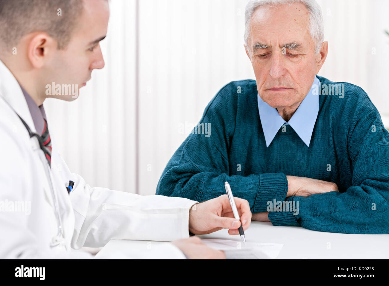 Young doctor writing instructing of therapy for senior patient Stock ...