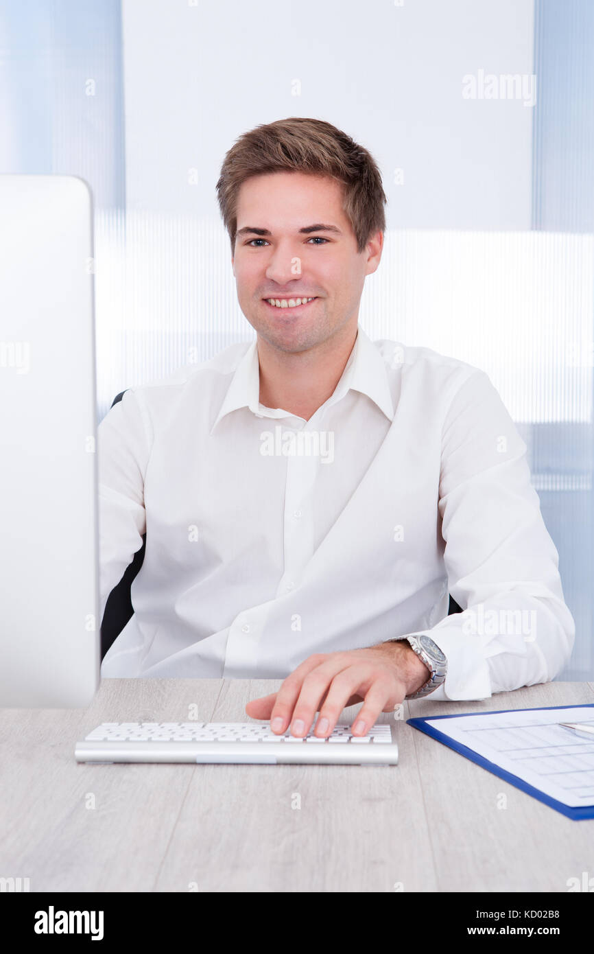 Portrait Of Young Businessman Using Computer At Desk Stock Photo - Alamy