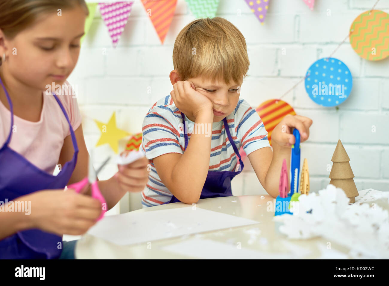 Portrait of sad little boy refusing to work in art and craft class of ...