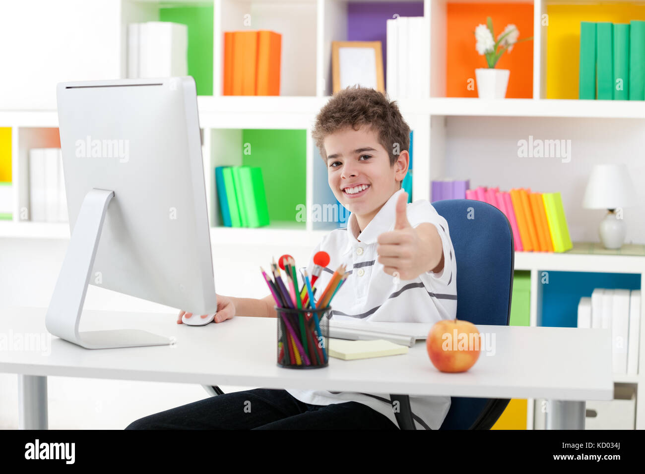 Boy sitting front of computer and showing thumb up Stock Photo - Alamy