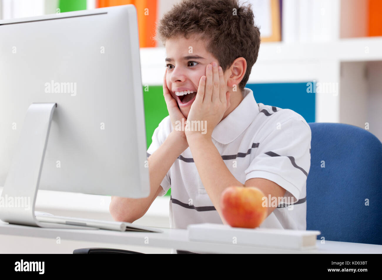 Surprised little boy looking at computer screen Stock Photo - Alamy