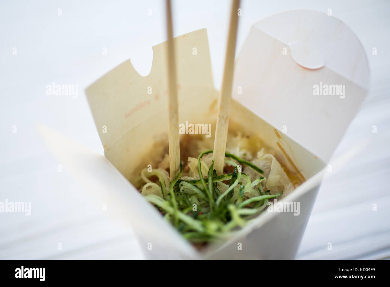 Noodles with pork and vegetables in take-out box on wooden table. Food ...