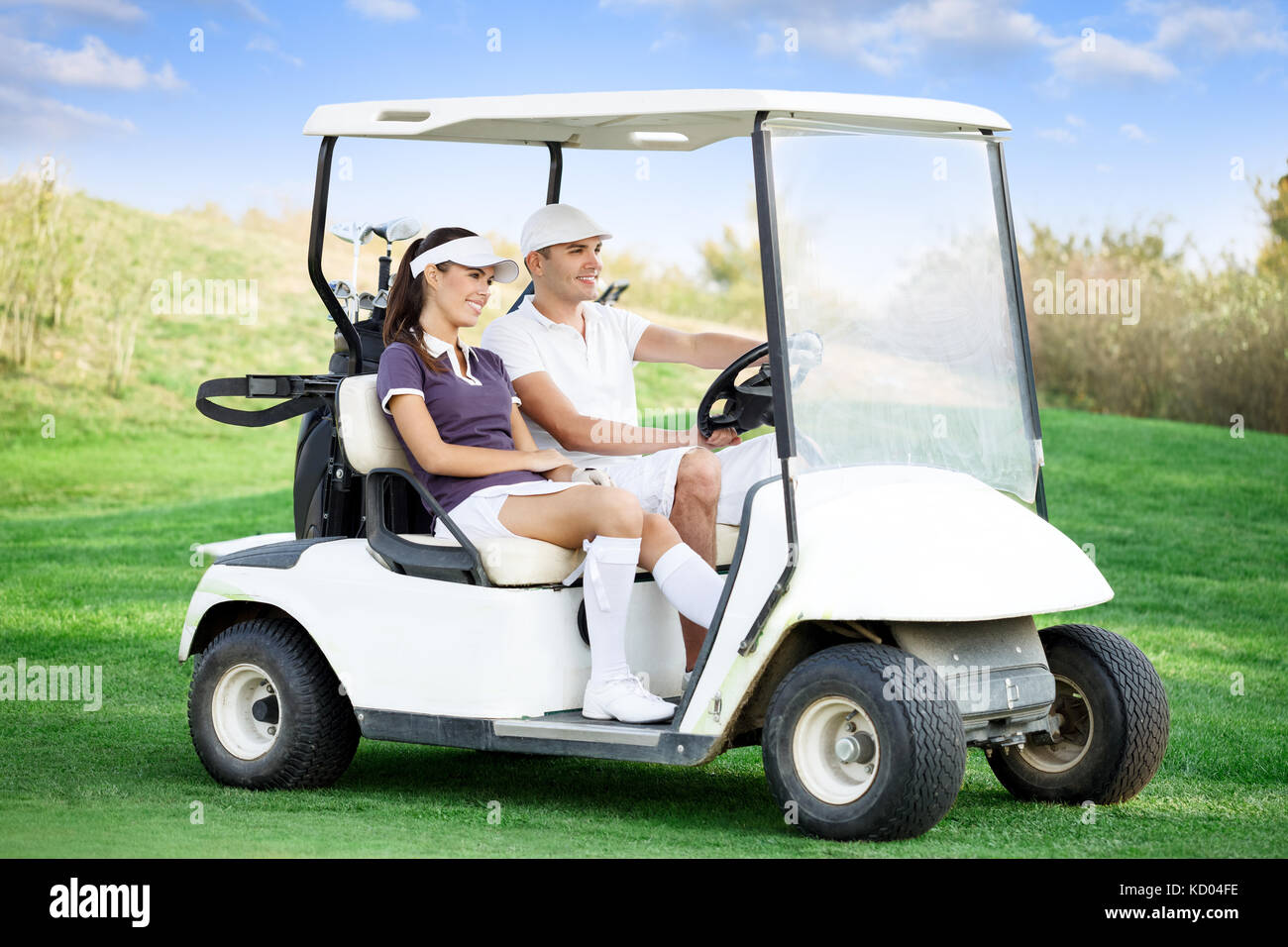 Young couple driving golf cart Stock Photo - Alamy