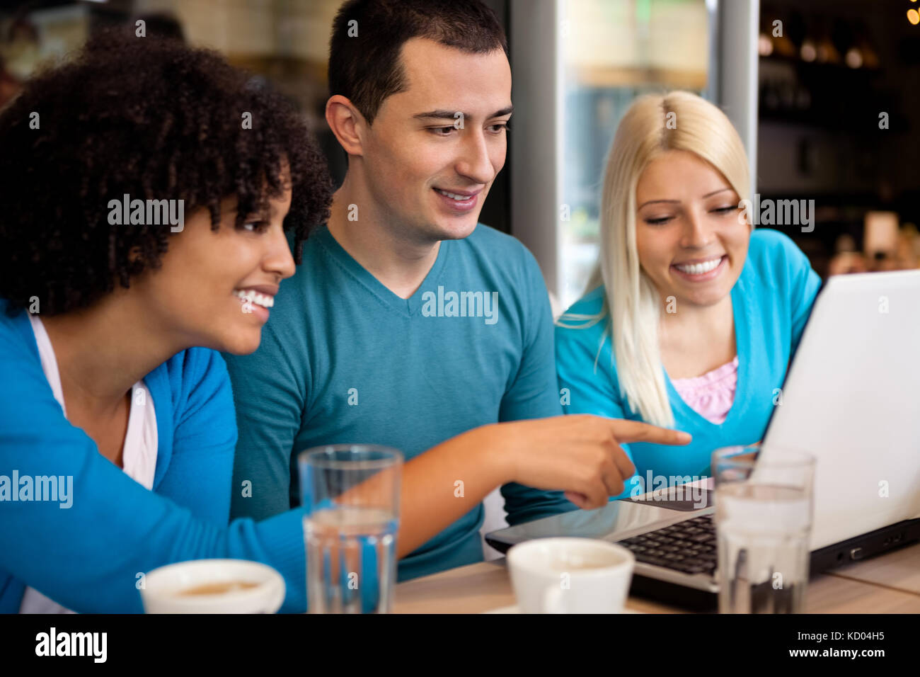 Smiling students in cafe with laptop Stock Photo - Alamy