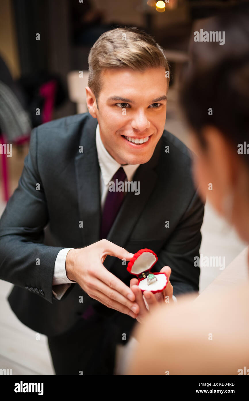 Young man romantically proposing to girlfriend and offering engagement ...
