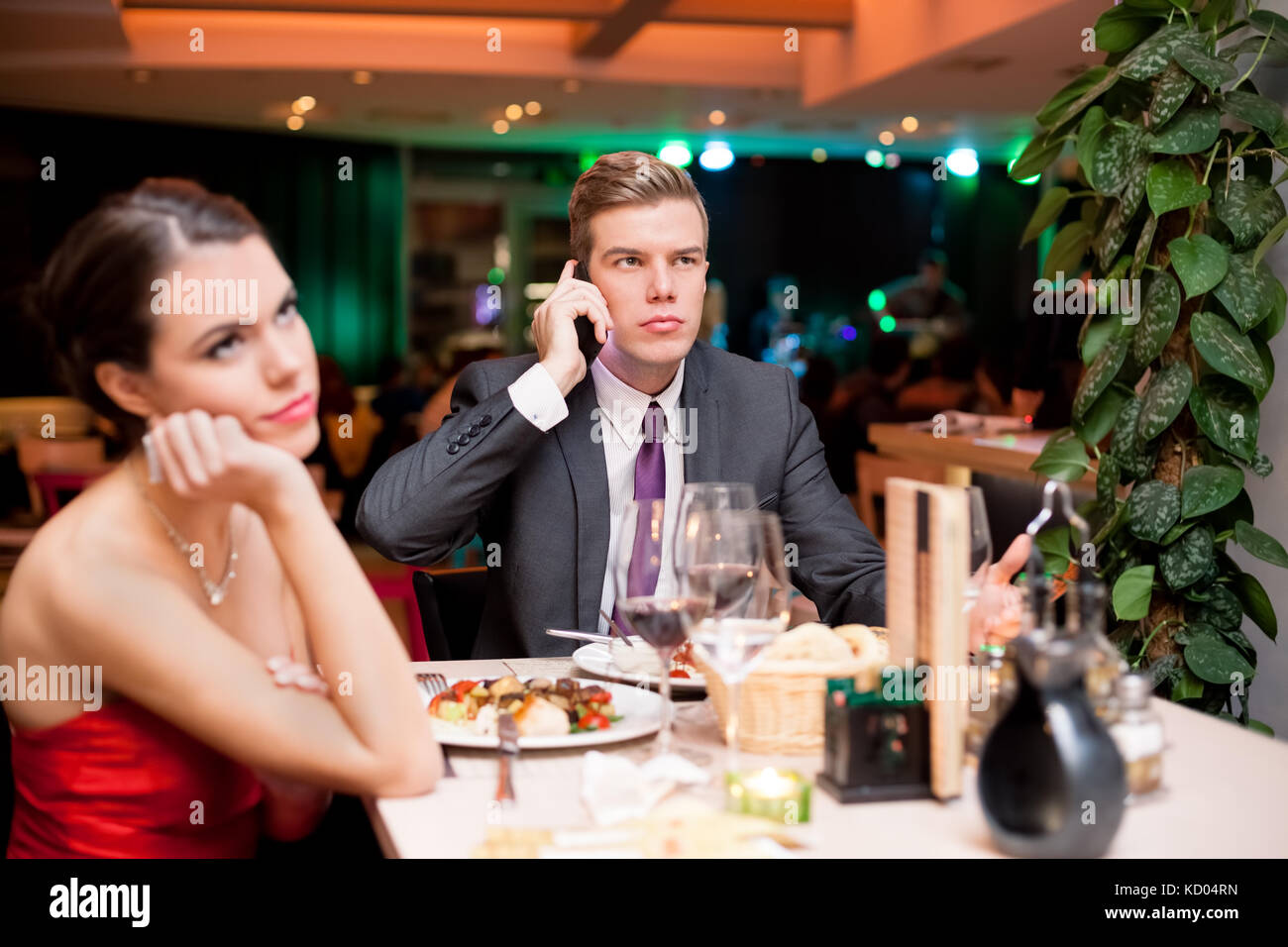 young woman bored to date while her boyfriend having business cell on ...