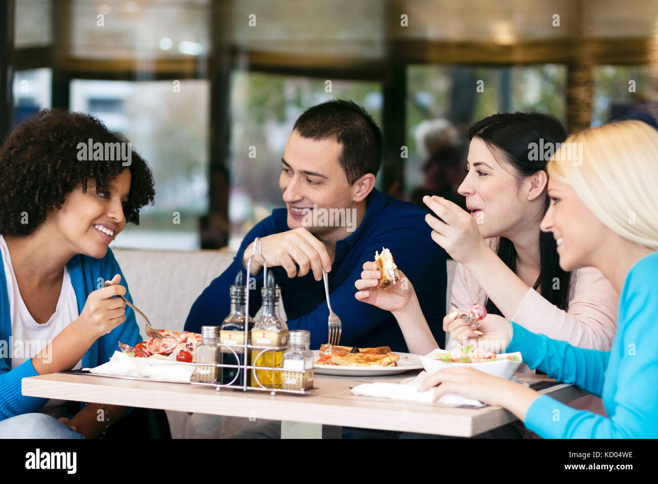 Four cheerful friends chatting while lunch in restaurant Stock Photo ...