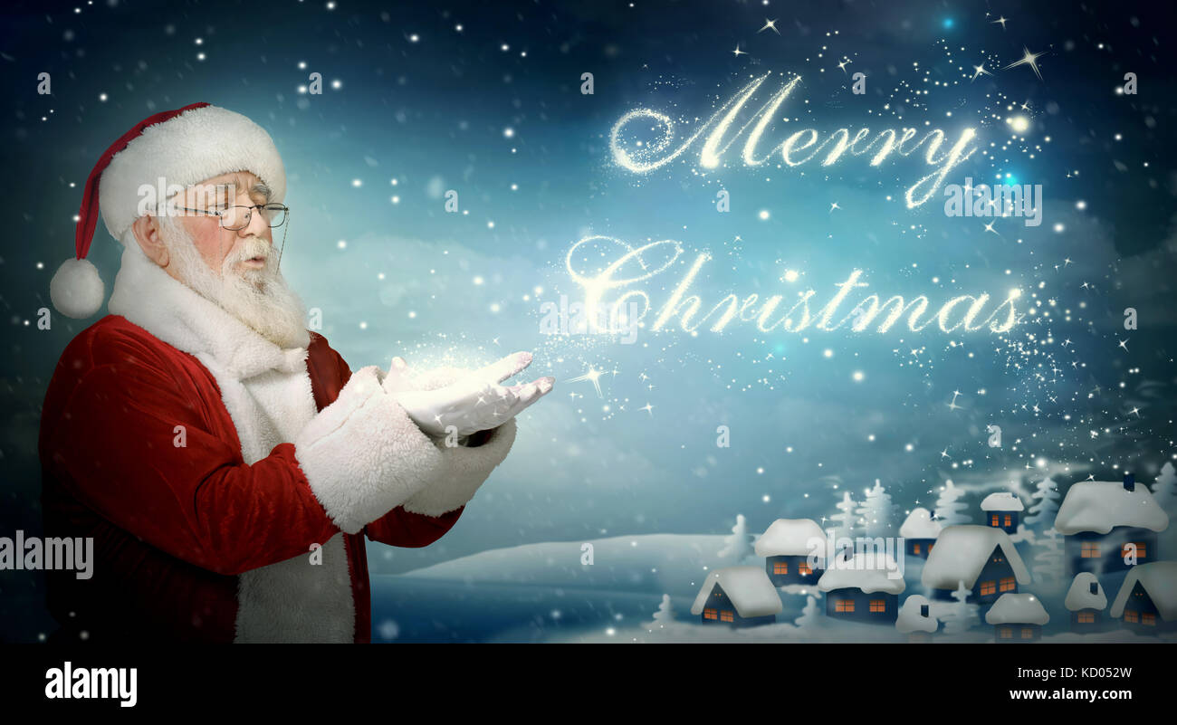 Santa Claus blowing “Merry Christmas” from snow to little town Stock ...