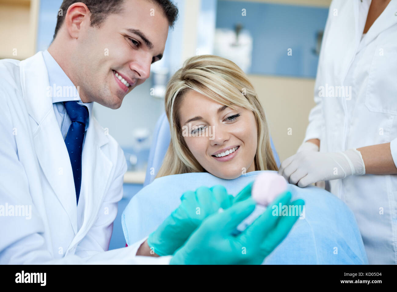 Dentist showing female patient her teeth sample or prosthesis at the ...